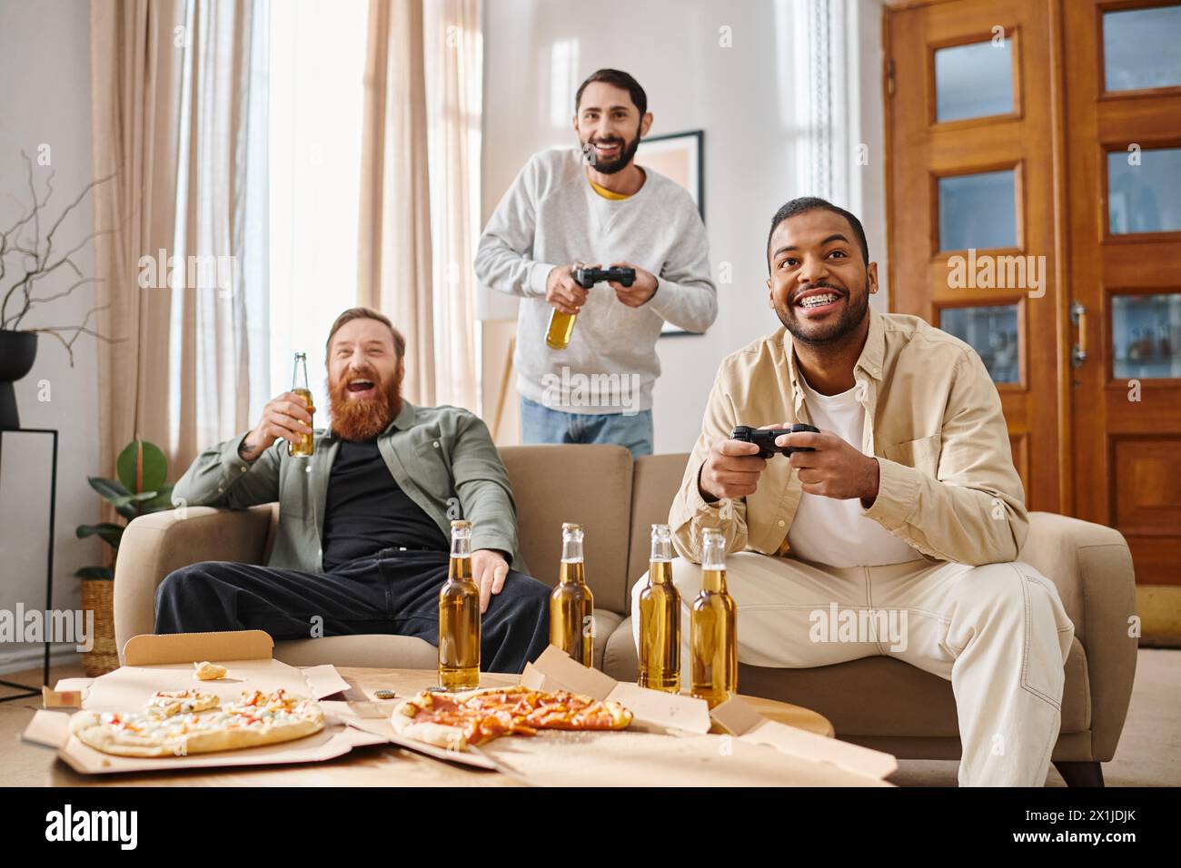 Three cheerful men, of different races, laughing and playing video ...