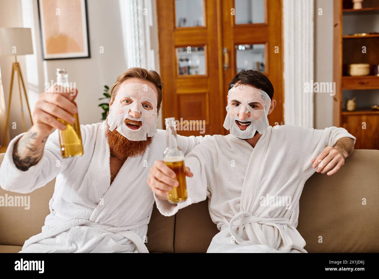 Two men in white robes share a fun moment, holding beer and wearing ...