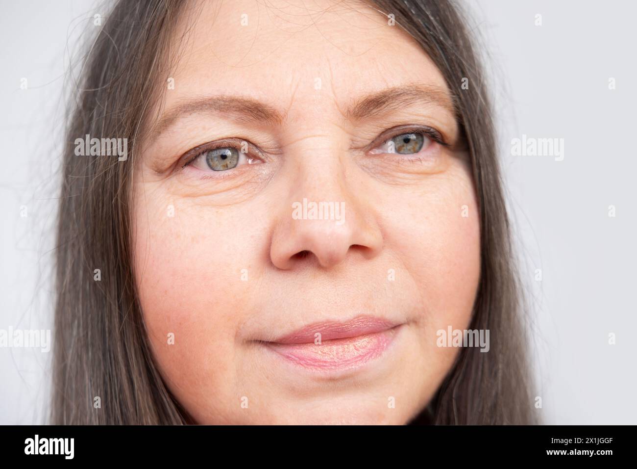 close up mature female face, aging woman 55 years old gazes herself in ...