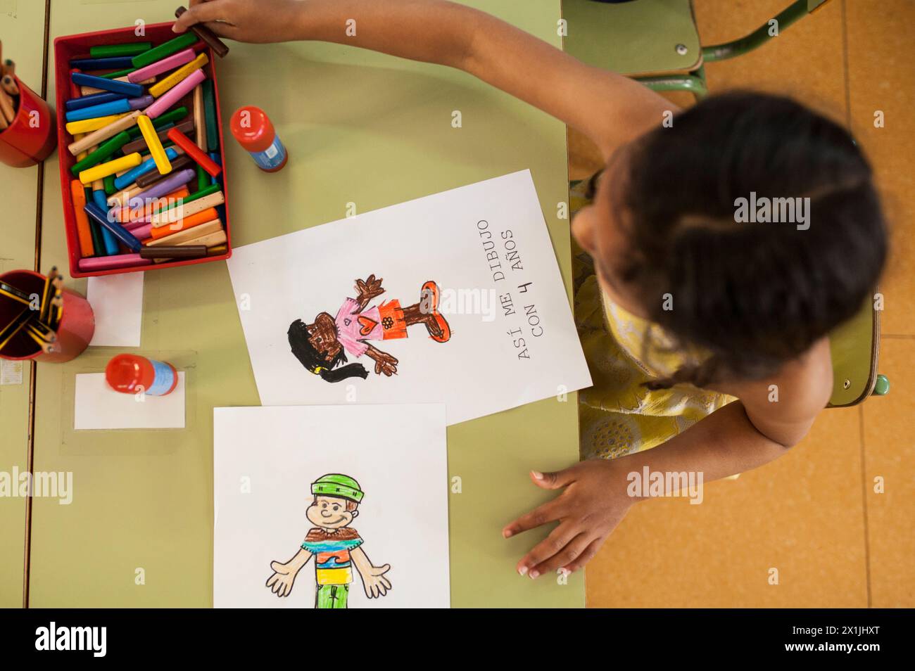 overhead view of a dark-skinned elementary school girl drawing with ...
