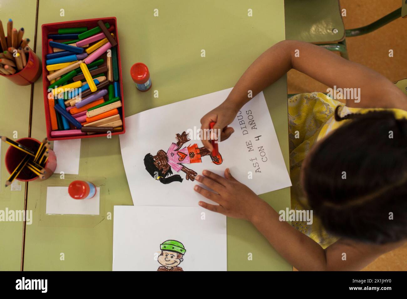 overhead view of a dark-skinned elementary school girl drawing with ...