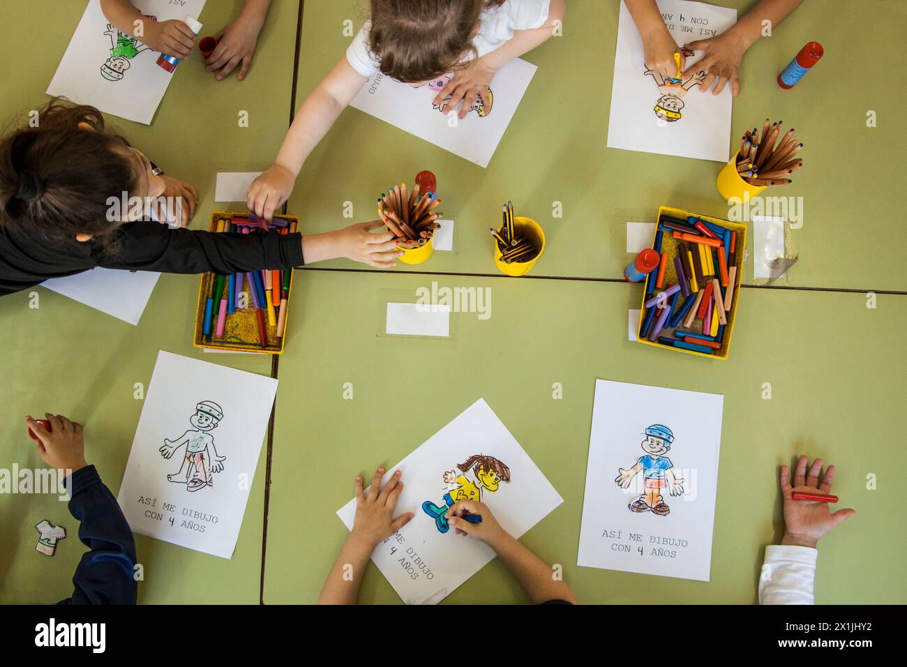 overhead view of several primary school children making a picture with ...