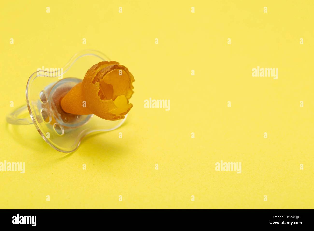 A chewed baby pacifier on a yellow background. Concept of teething in ...