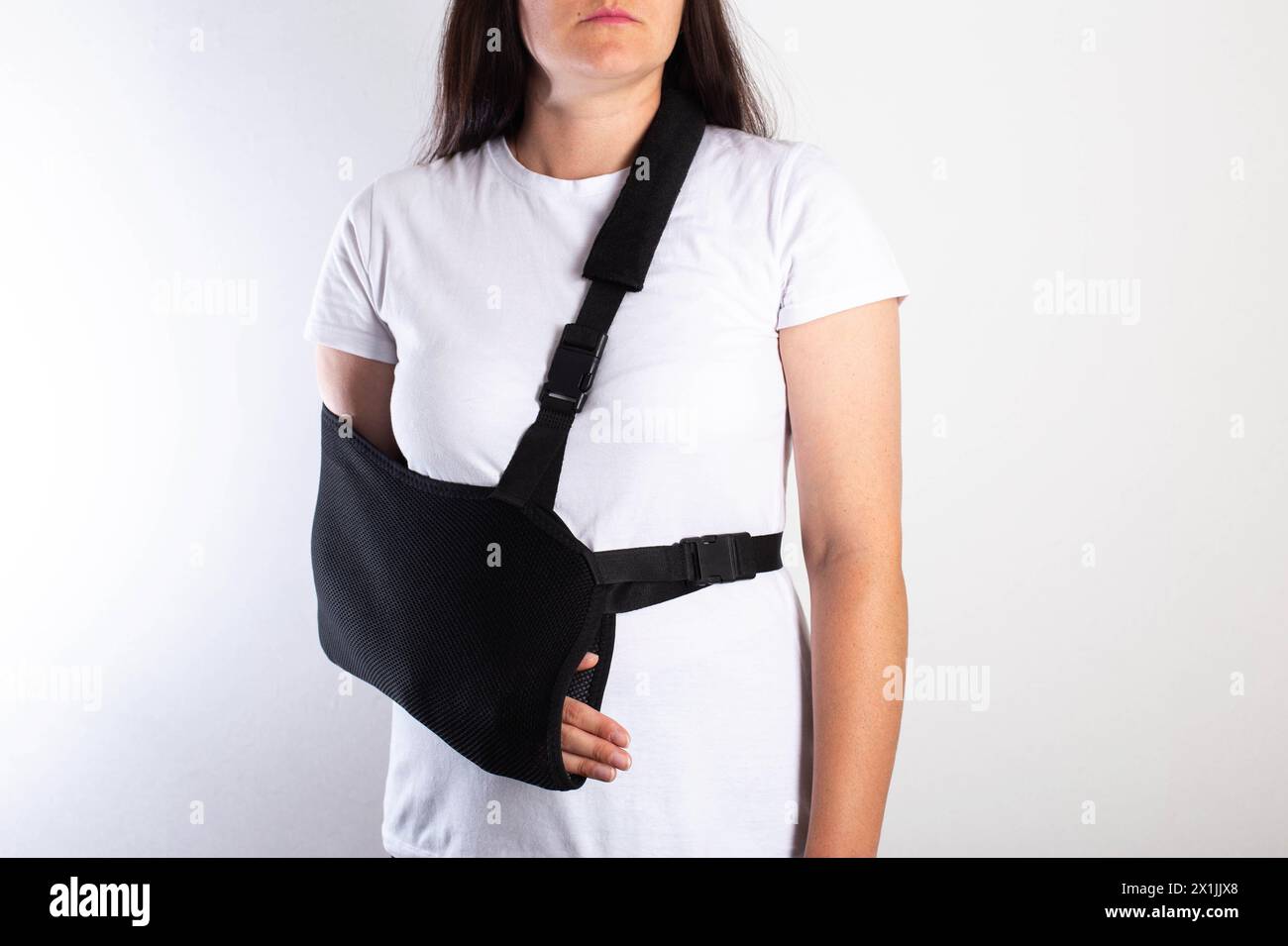 A girl on a white background with a black supporting medical bandage ...