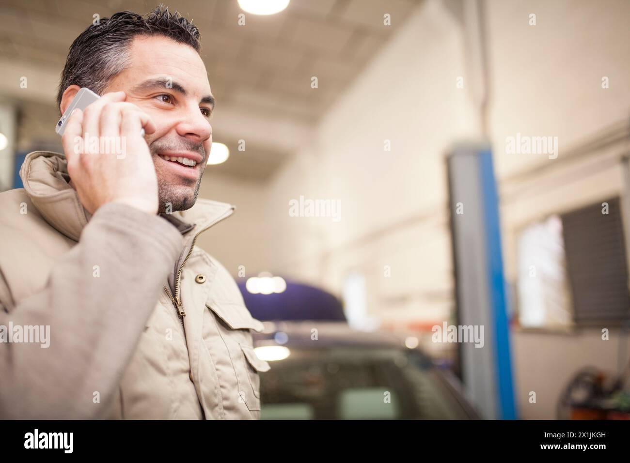 mechanic answers a phone call while checking vehicle levels in a ...