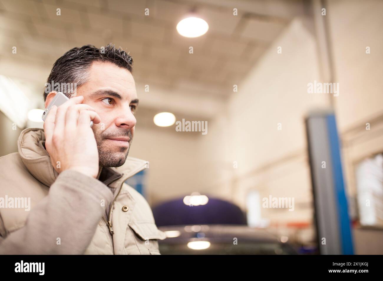 mechanic answers a phone call while checking vehicle levels in a ...