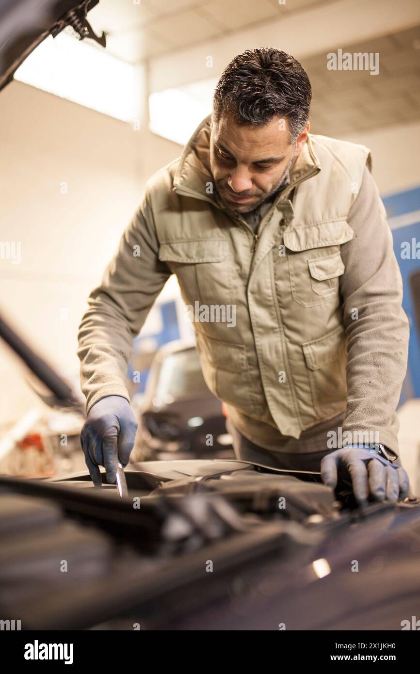 mechanic checks fluid levels of car in mechanical workshop Stock Photo ...