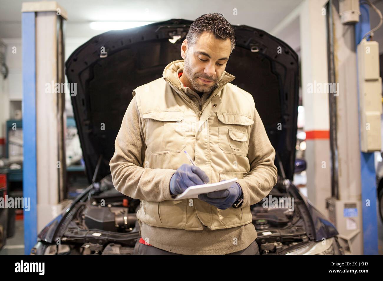 mechanic takes notes while checking levels of vehicle in mechanical ...
