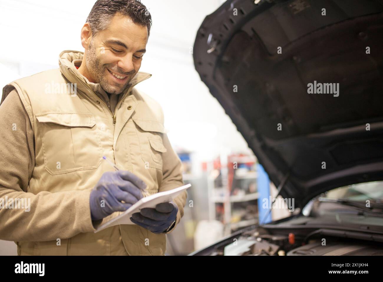 mechanic takes notes while checking levels of vehicle in mechanical ...