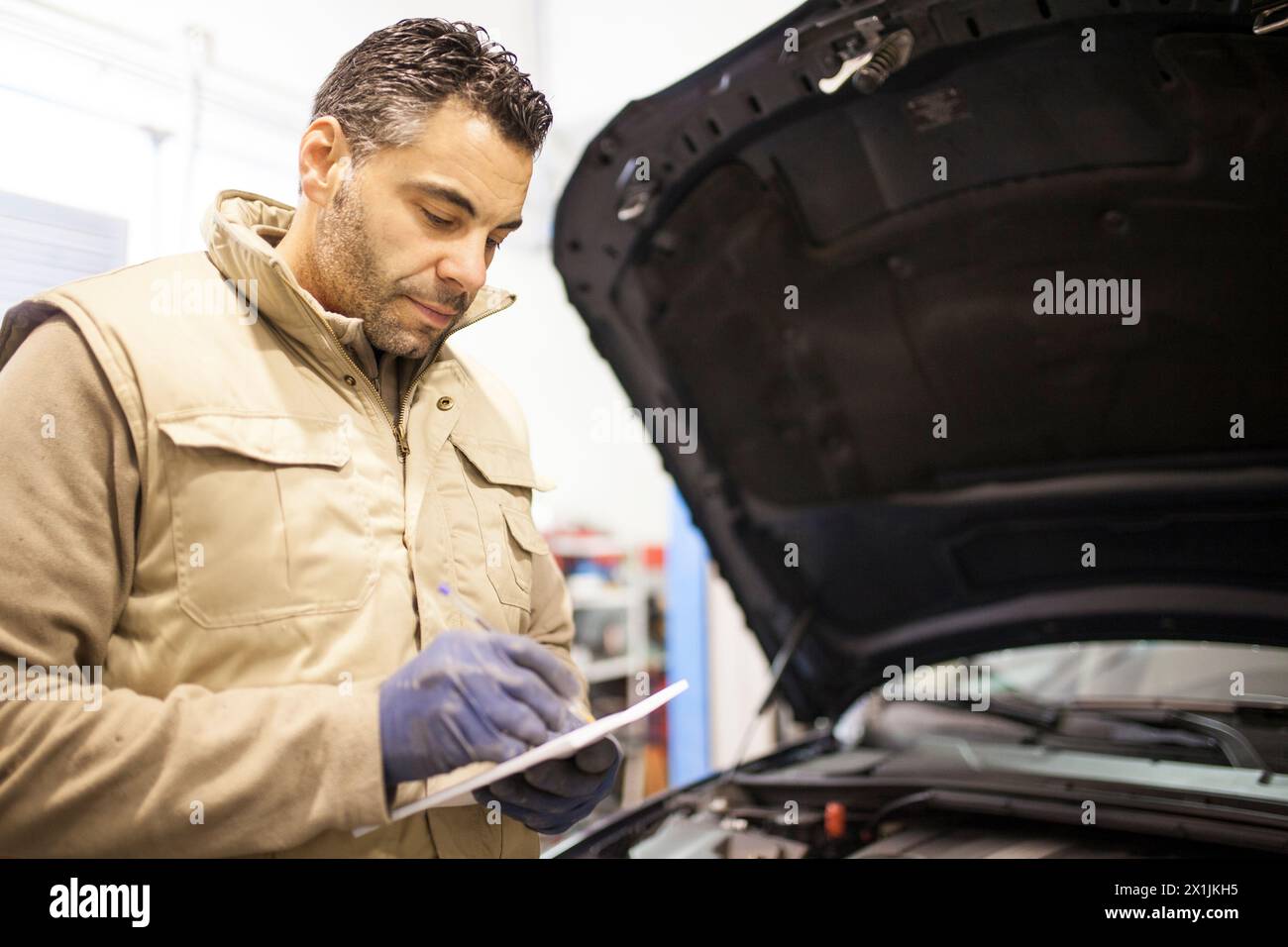 mechanic takes notes while checking levels of vehicle in mechanical ...