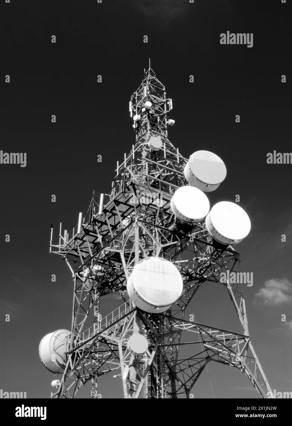 Roadside communications mast with telecoms installations against dark ...