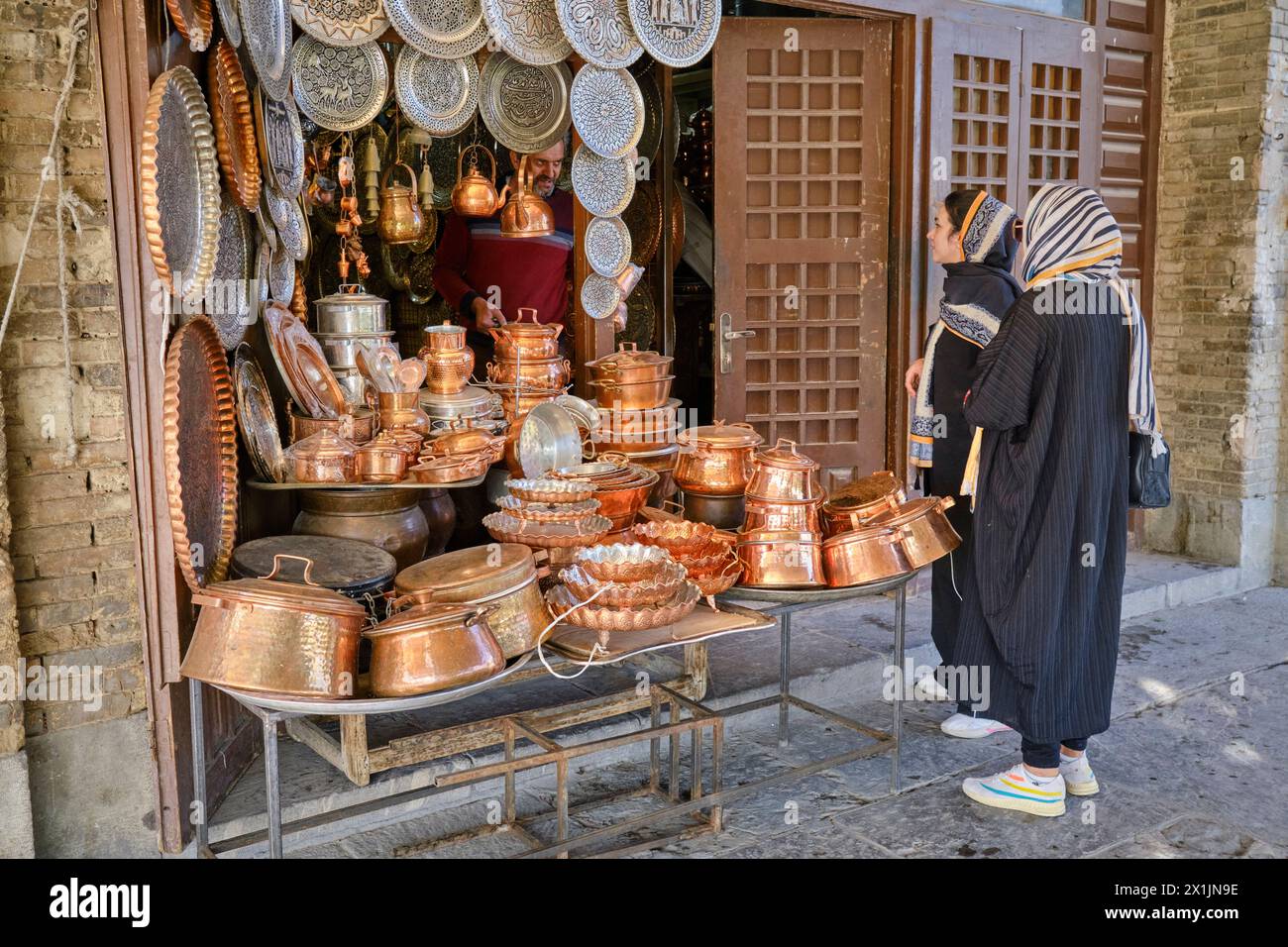 Two Iranian women buy copper cookware in a small shop in Naqsh-e Jahan ...