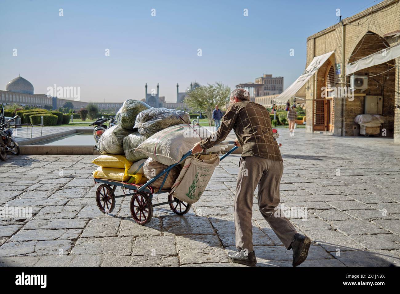 An older porter pushes his heavily loaded cart in the Naqsh-e Jahan ...