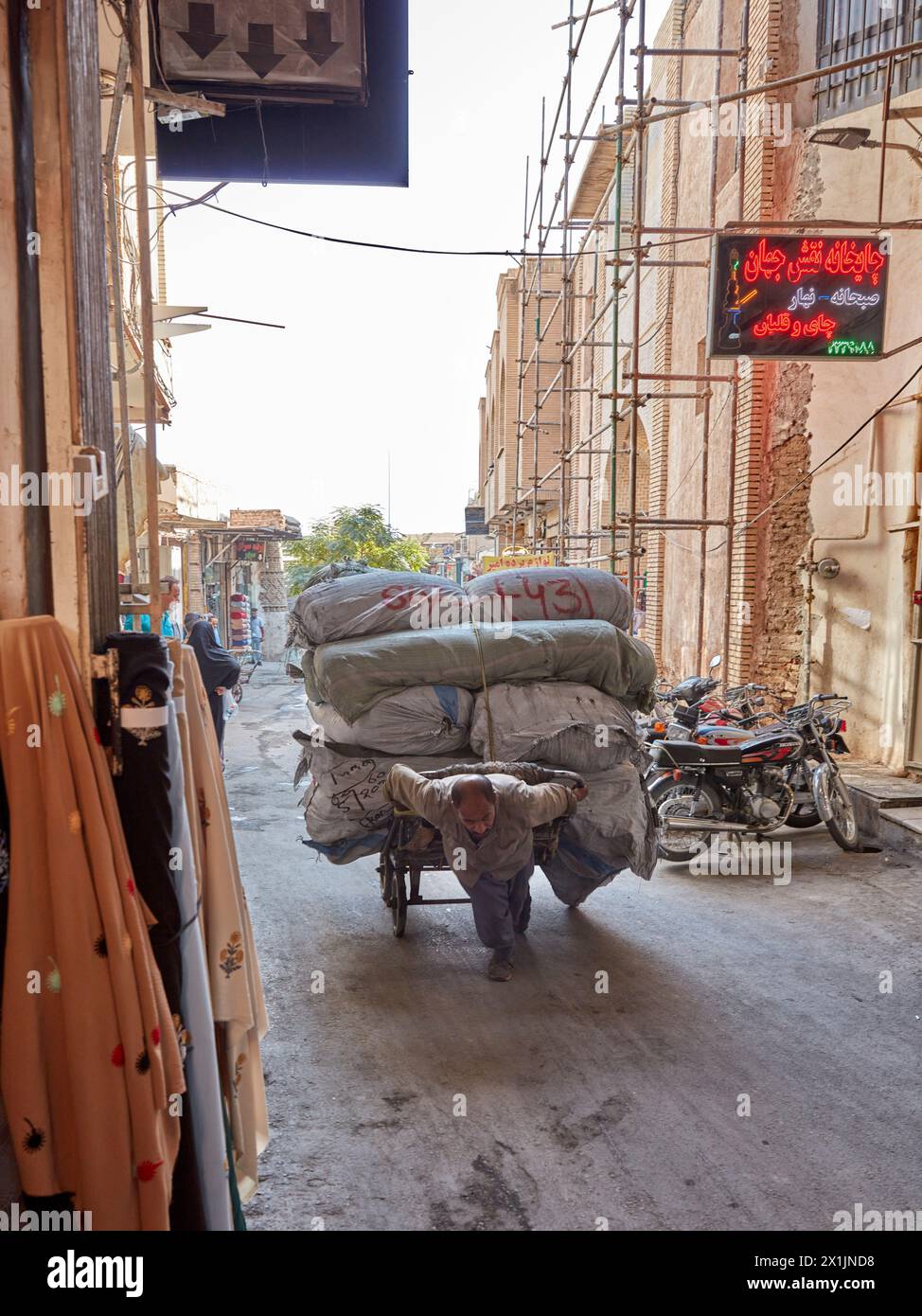 A porter pulls his heavily loaded cart in a narrow street near the ...