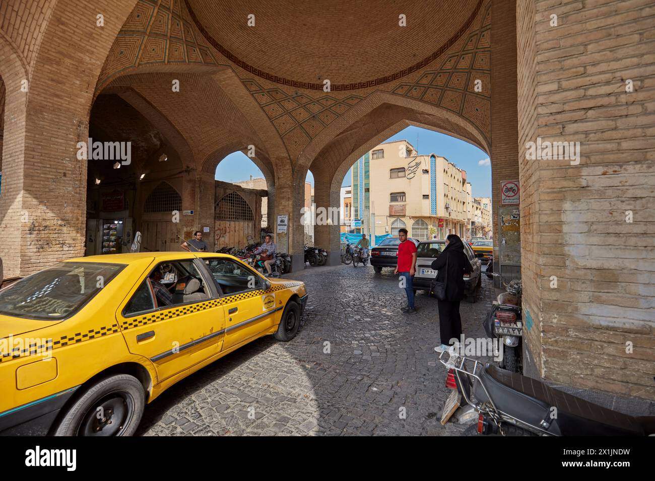 A yellow taxi cab drives through an archway with vaulted roof in the ...