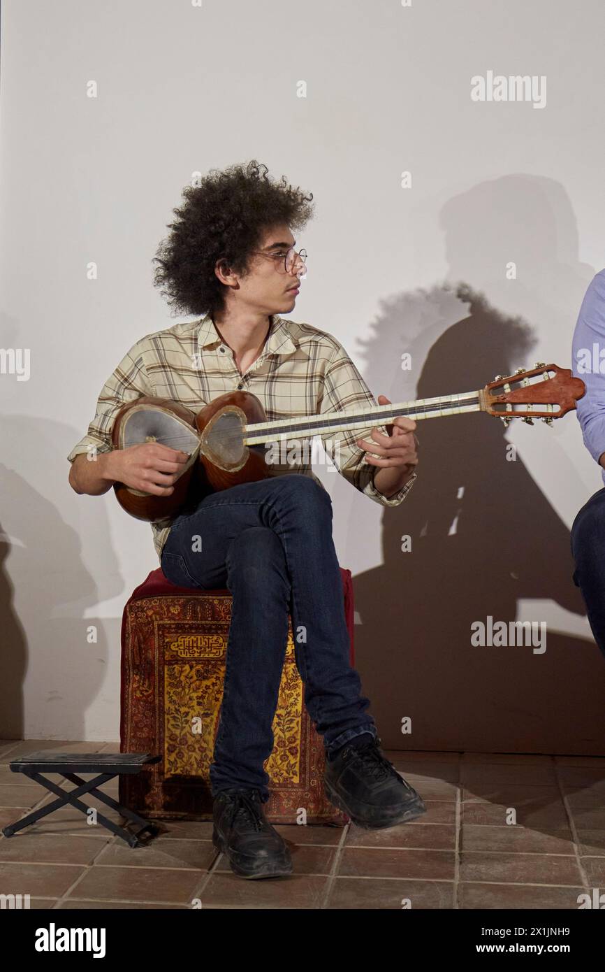 A young Iranian man plays tar, a long-necked waisted lute family string ...