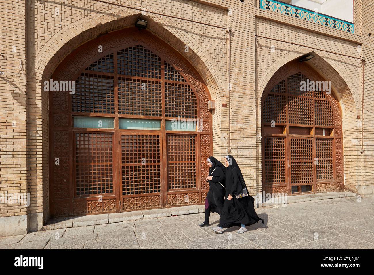Two young Iranian women wearing black chadors walk together in Naqsh-e ...