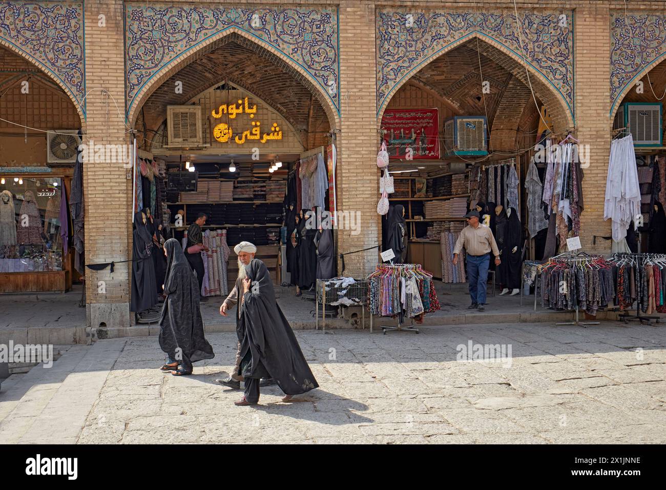Traditionally dressed Iranian people walk in a narrow street in the ...