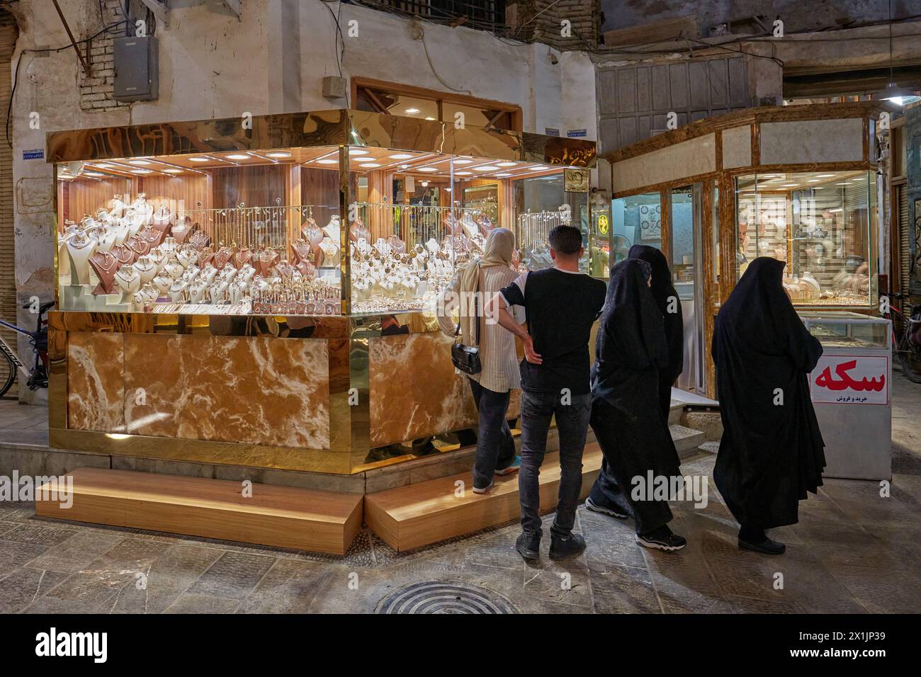 People look at golden jewelry displayed in a small shop window in the ...