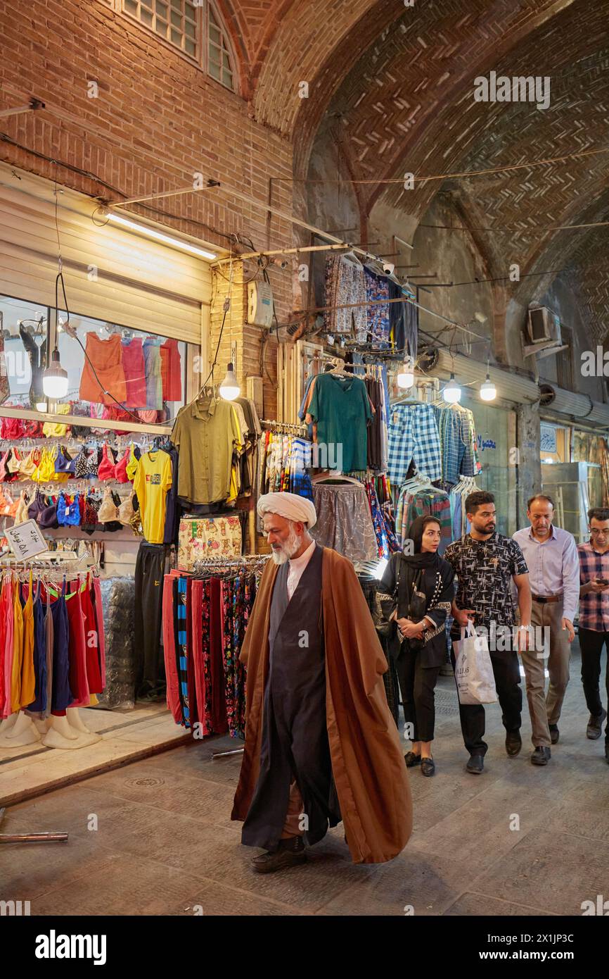 A man wearing traditional Muslim religious clothes walks in a narrow ...