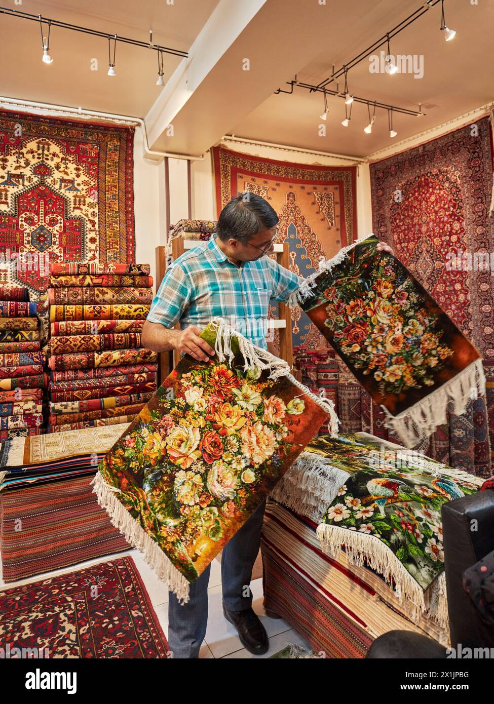 Seller in a carpet store shows his wares. Isfahan, Iran Stock Photo - Alamy