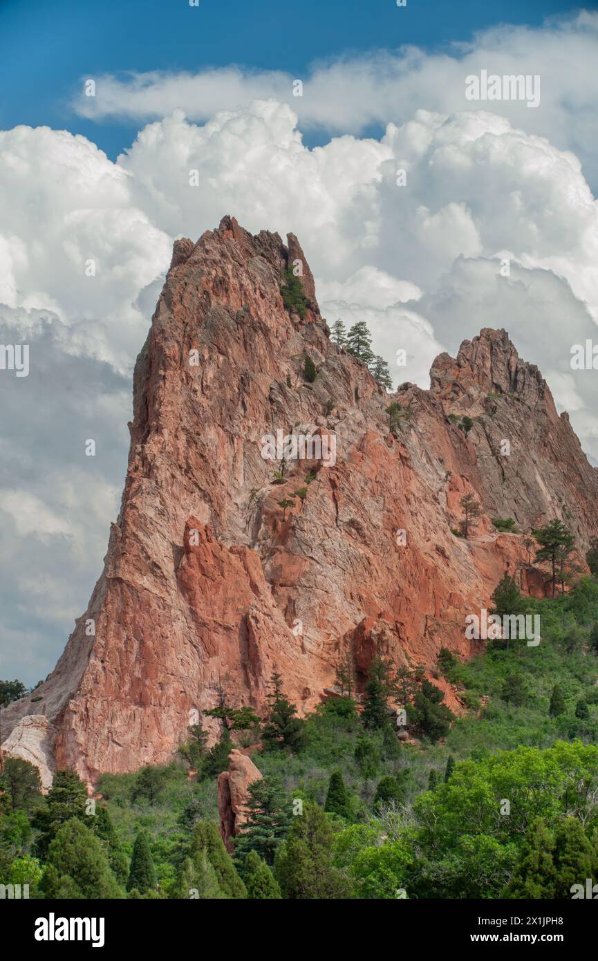 A towering red rock formation stands under a vast blue sky ...