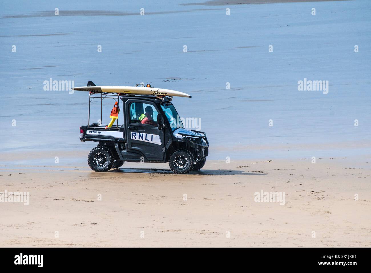A small RNLI emergency response vehicle patrolling Fistral Beach in ...