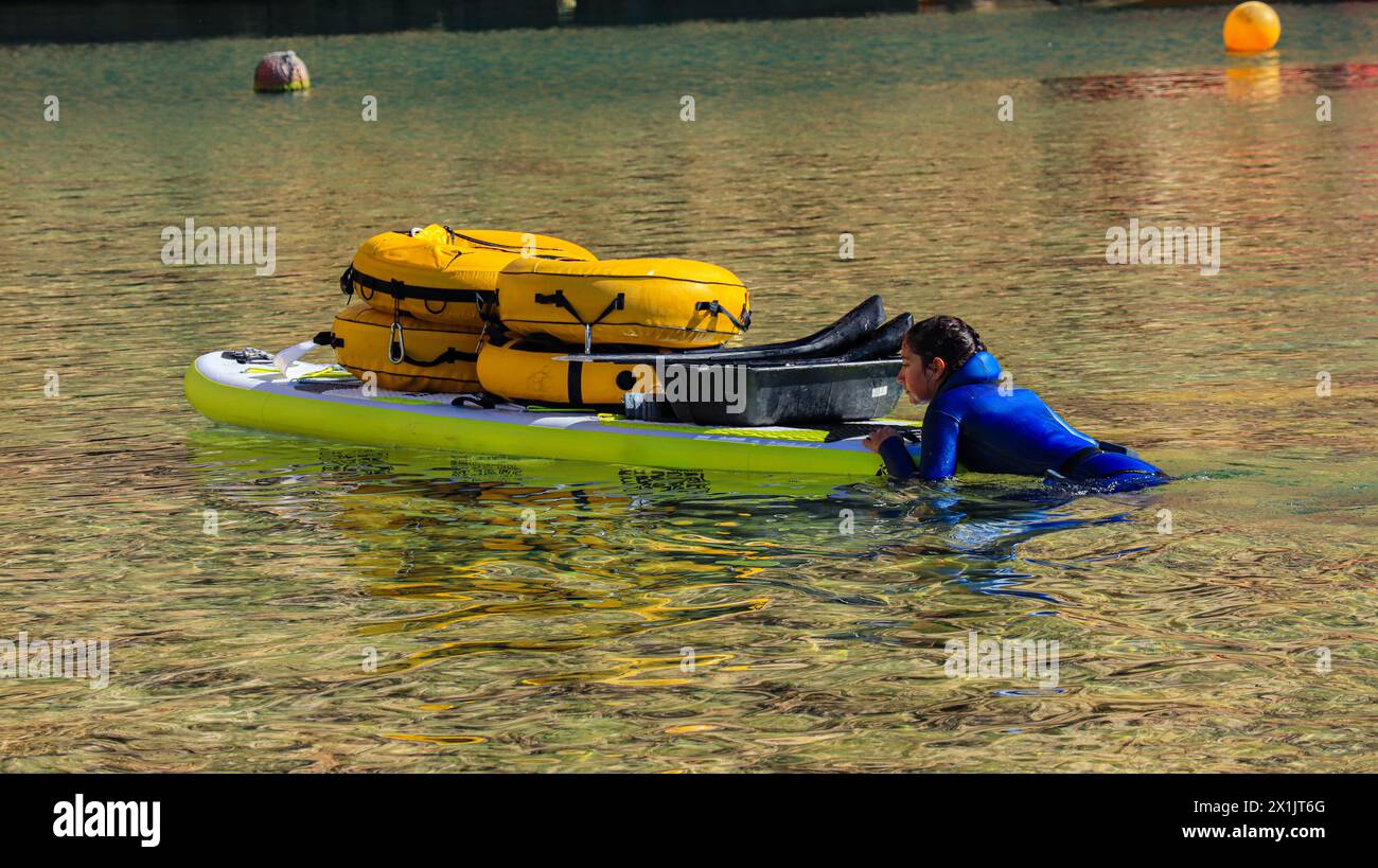 A free-diver swims with a paddleboard on the way to the dive site Stock ...