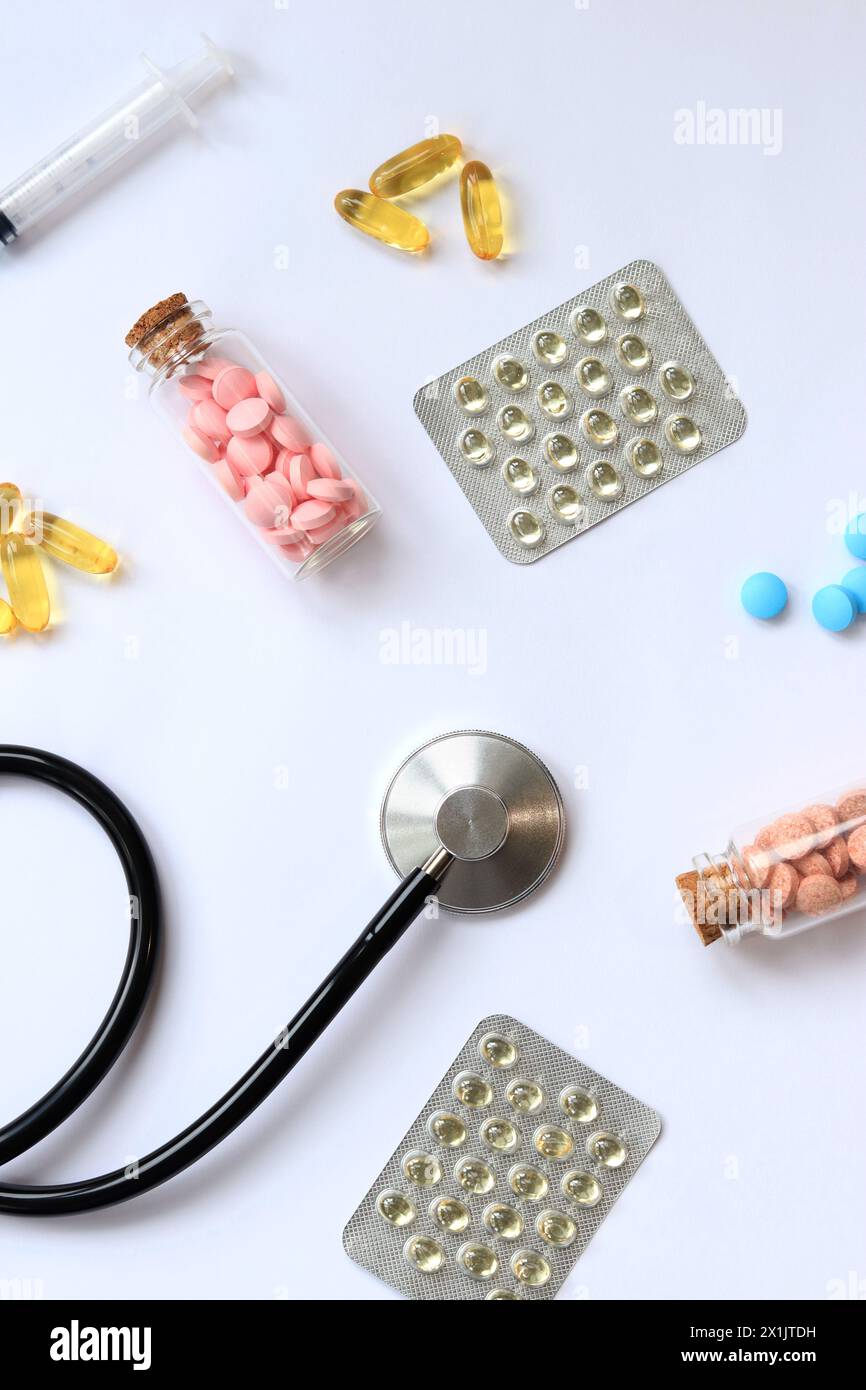Stethoscope on a white background, top view. Medical instrument and different medicines, tablets ...