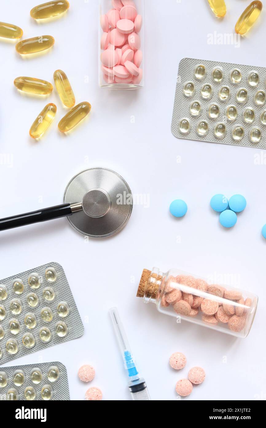 Stethoscope on a white background, top view. Medical instrument and different medicines, tablets ...