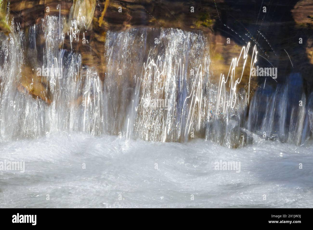 A tranquil cascade of water flows over natural rocks, creating a ...