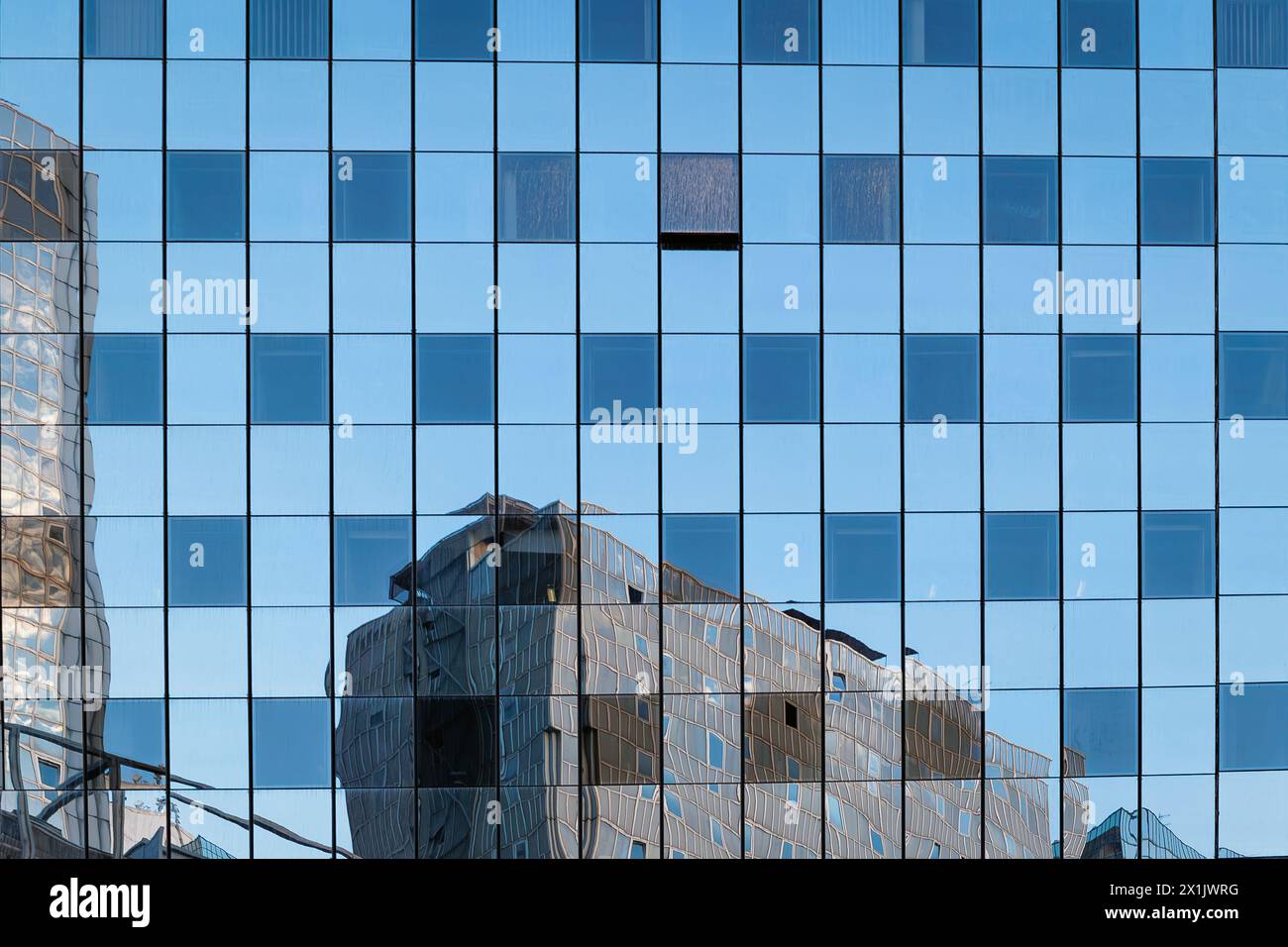 Facade of a skyscraper in which the surrounding buildings and blue sky ...