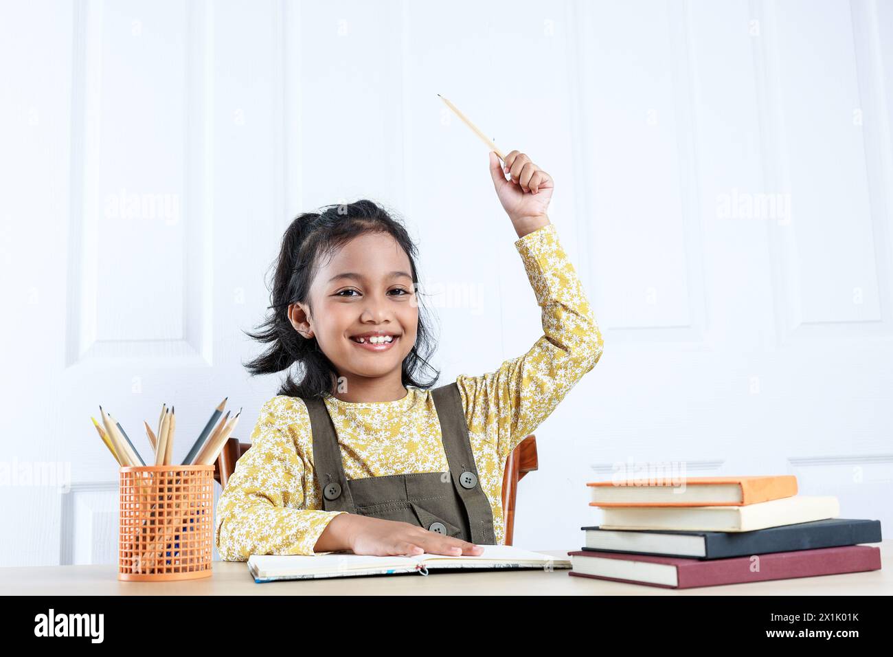 Asian Girl Holding Up Pencil Pointing While Doing Homework, on White ...