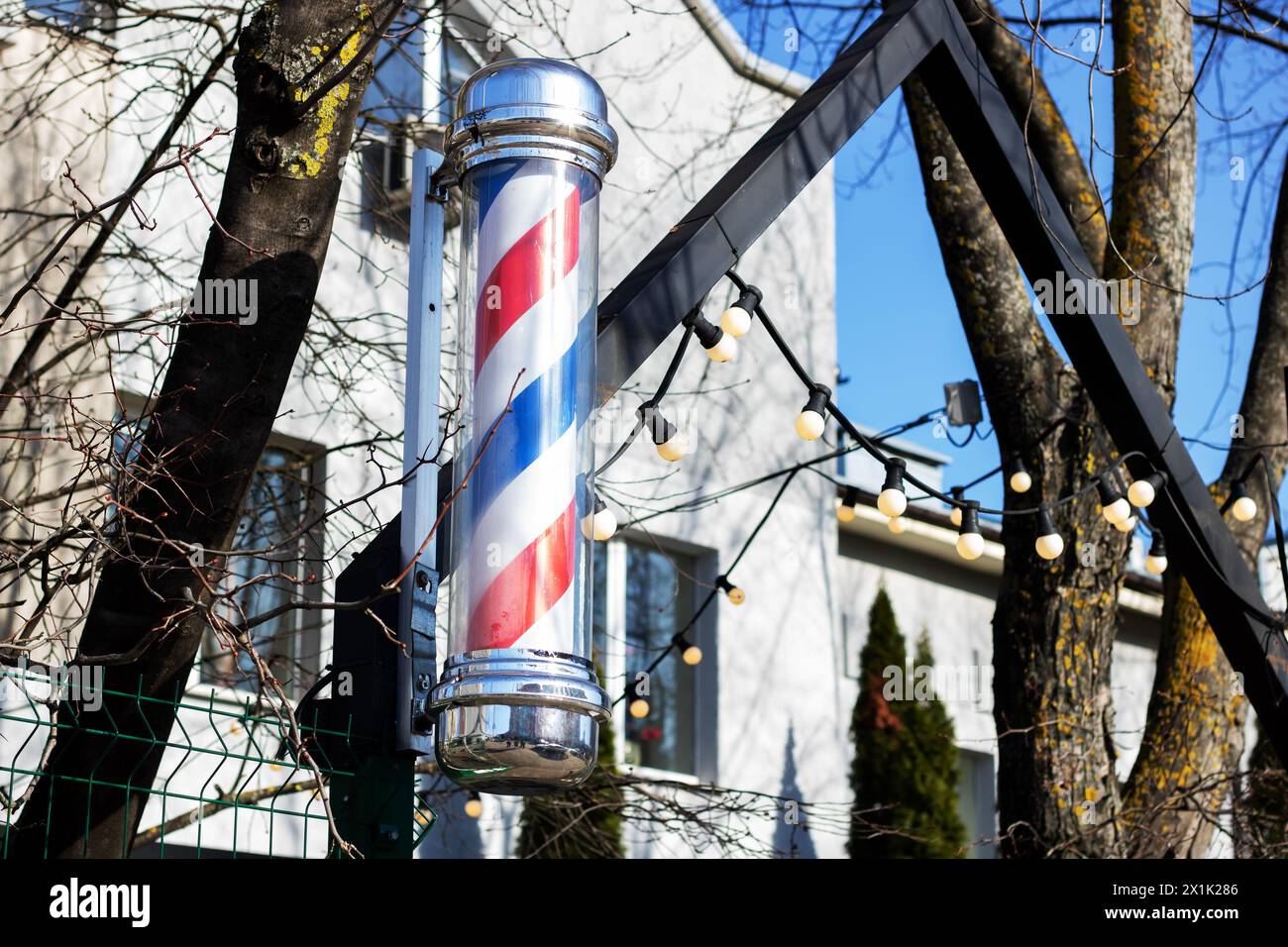 A traditional red, white, and blue barber pole is displayed against the ...