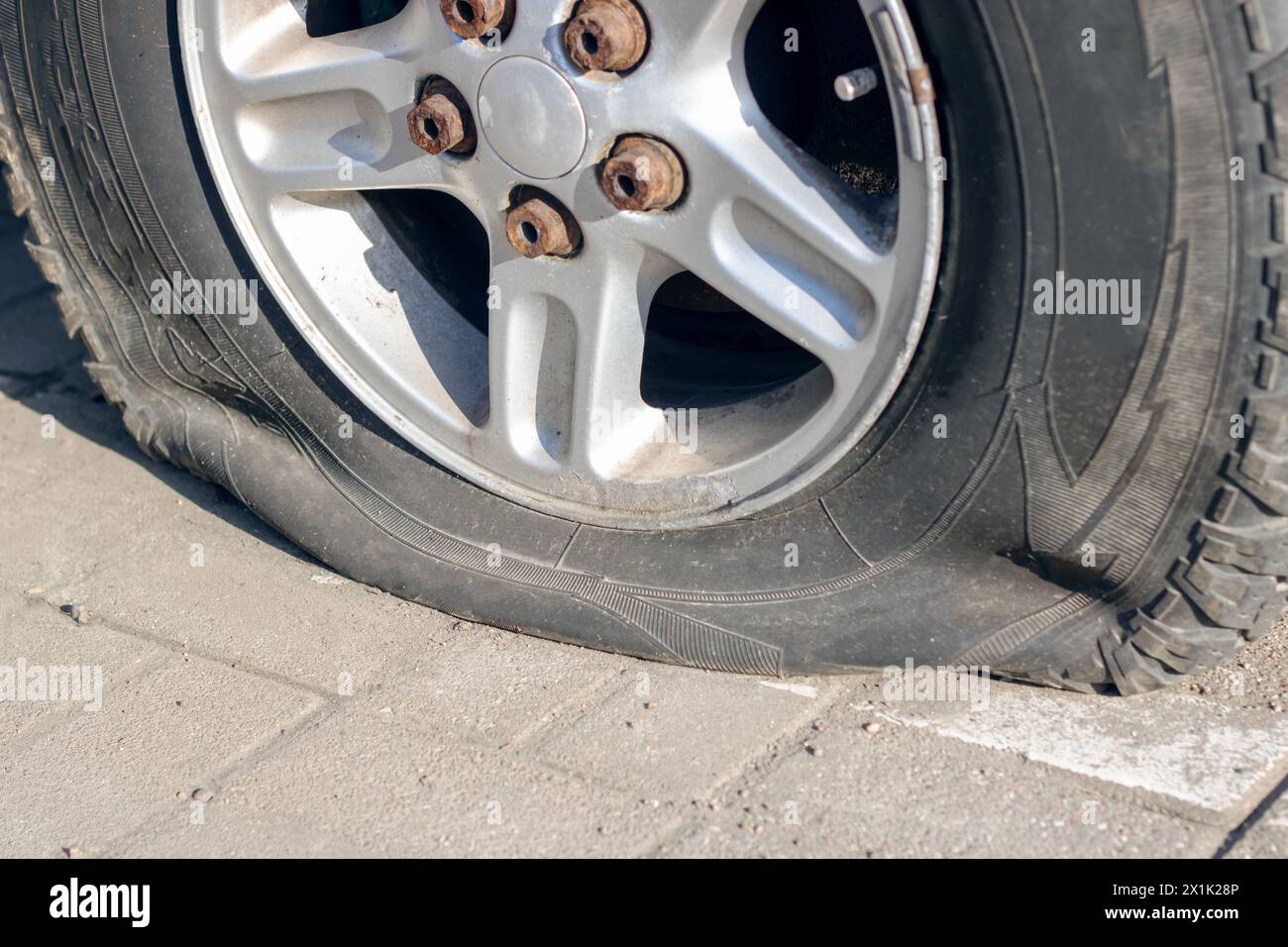 A car with a flat automotive tire on the side of the road, showing its ...