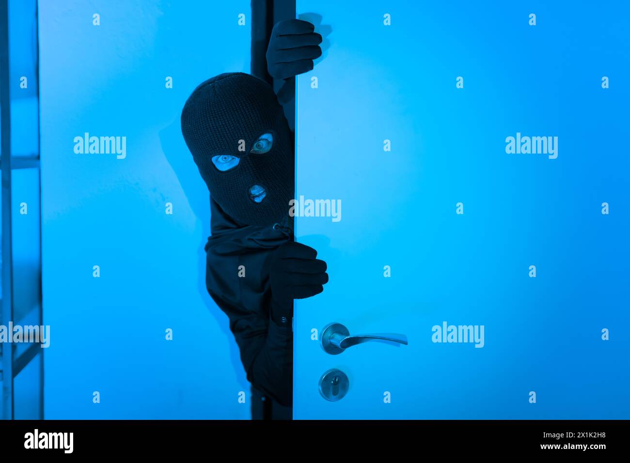 Burglar peeking from behind the door at night Stock Photo - Alamy