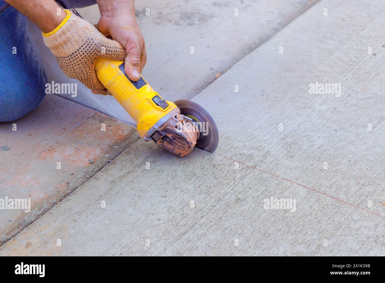 After pouring concrete, construction worker cuts foundation using ...