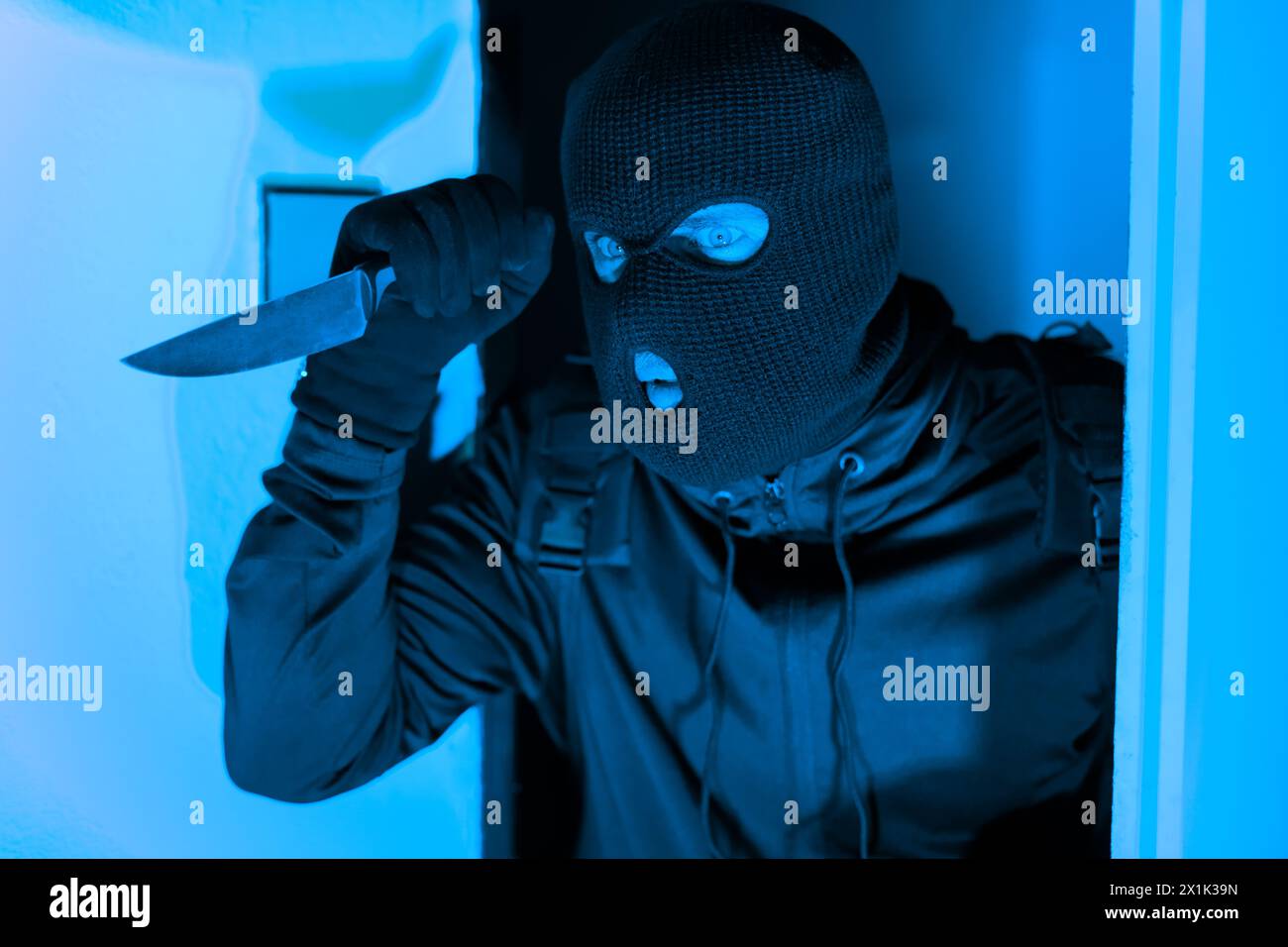 Masked thief peeking around door, break in Stock Photo - Alamy