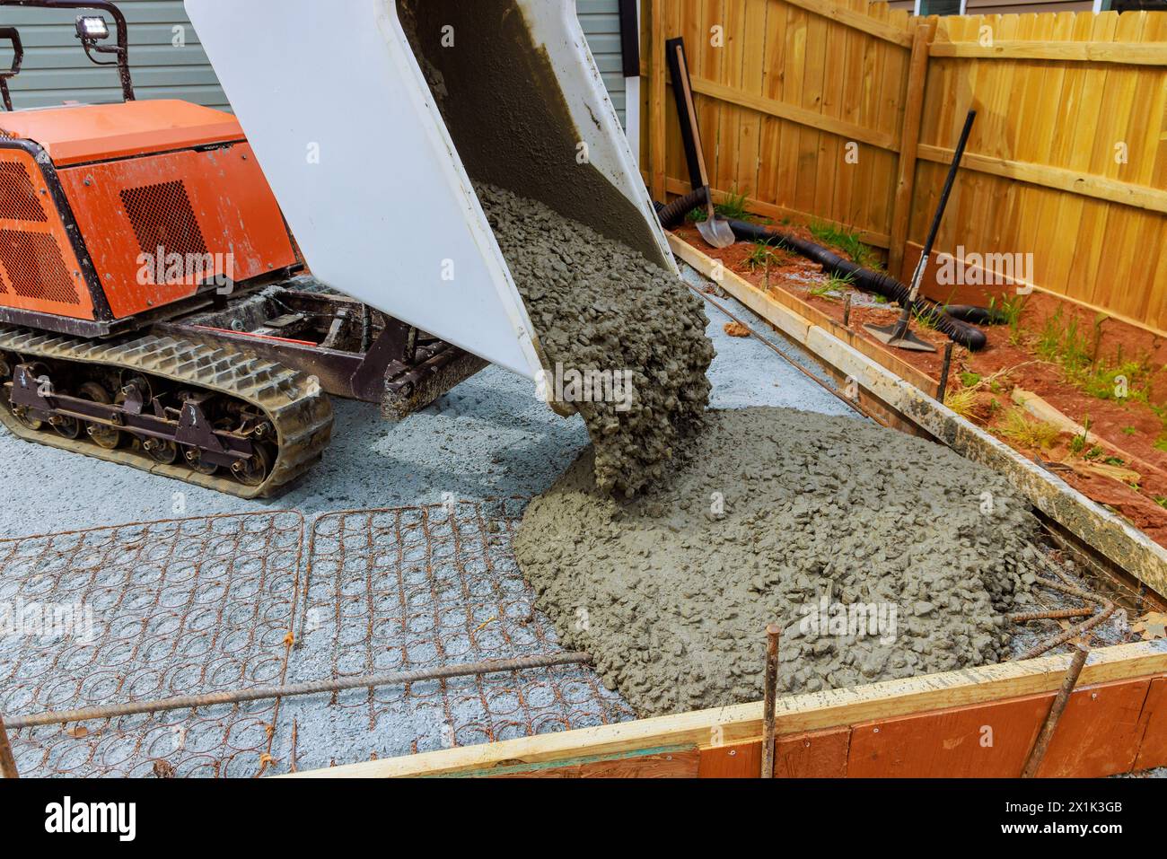 Wet cement is poured into framework during foundation construction ...