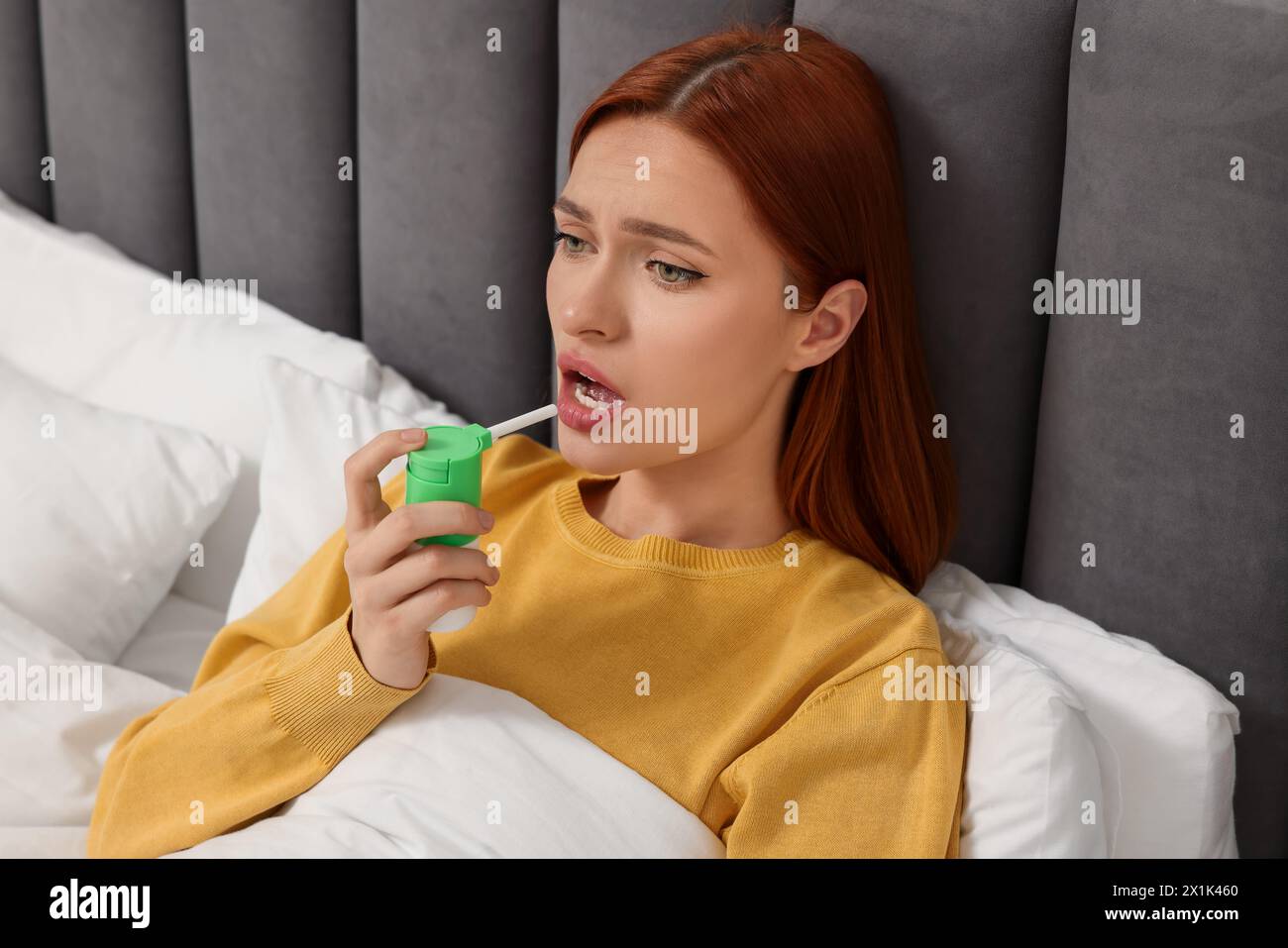 Young woman using throat spray in bed Stock Photo - Alamy