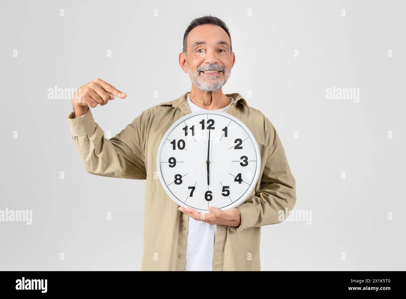 Smiling man holding a large clock on white background Stock Photo - Alamy