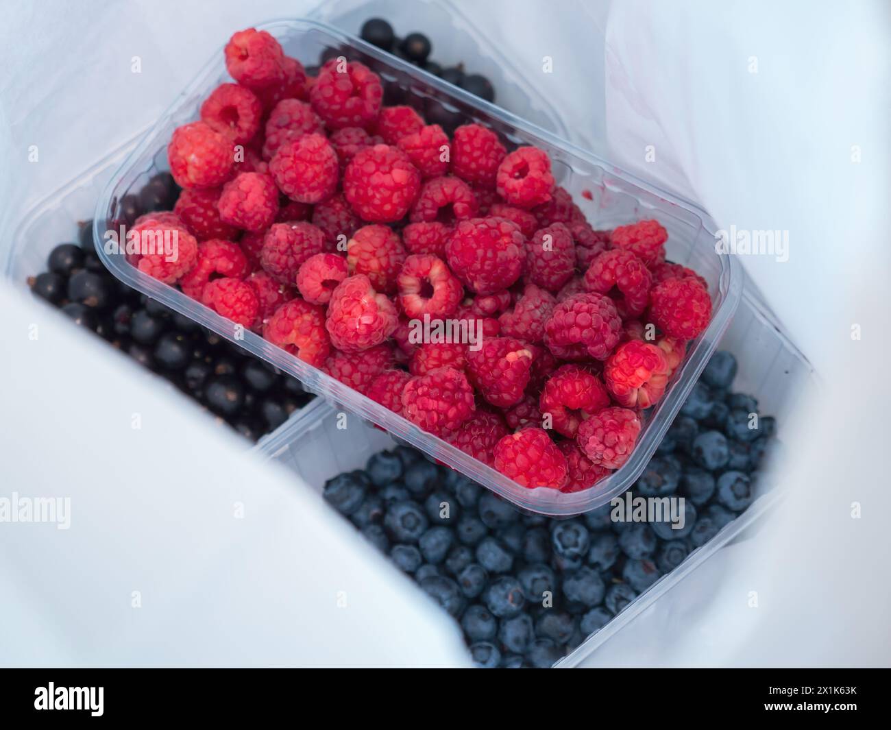 Three plastic containers with raspberries, blueberries and black ...