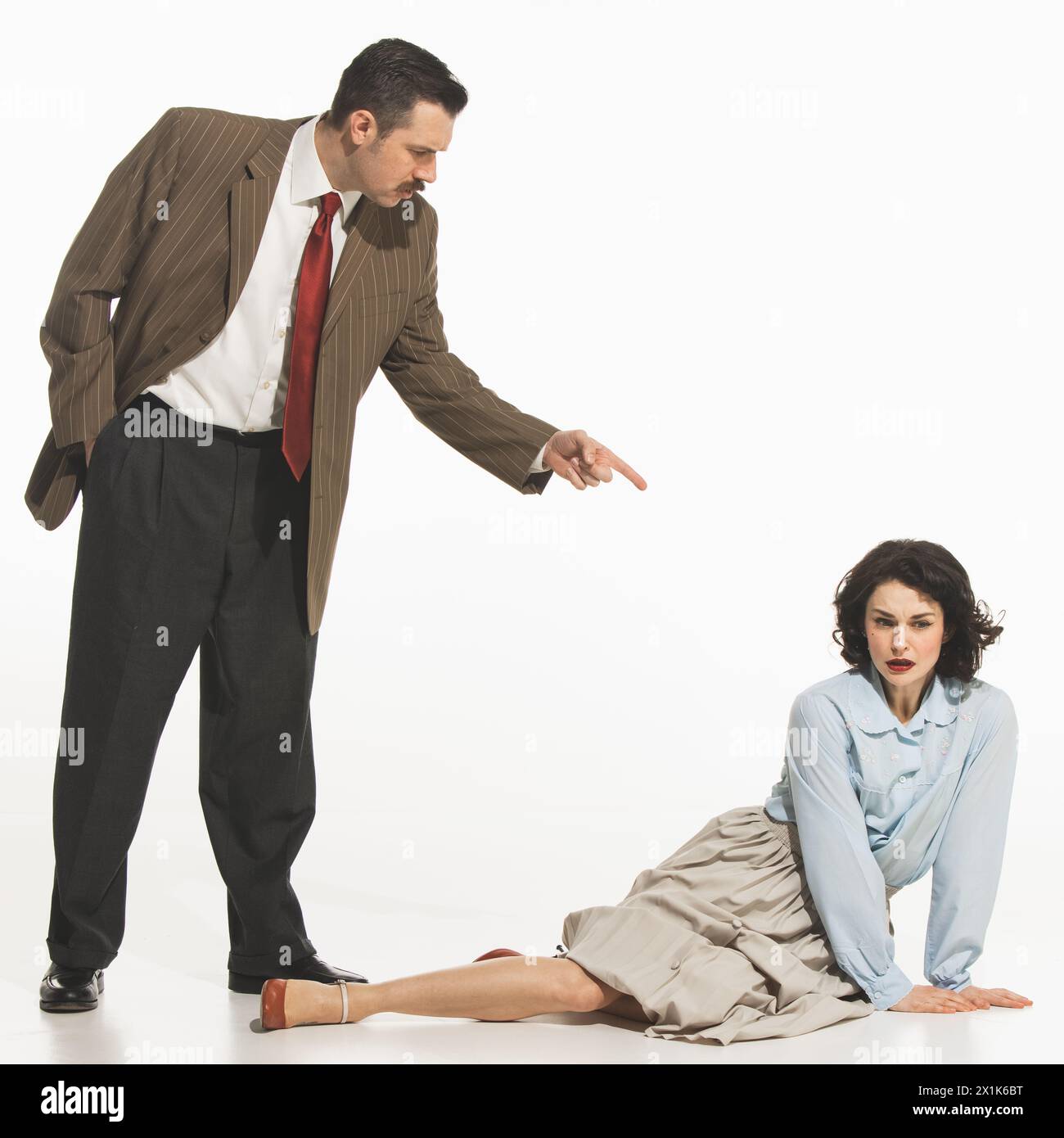 Man in suit pointing at seated woman on the floor, suggesting ...