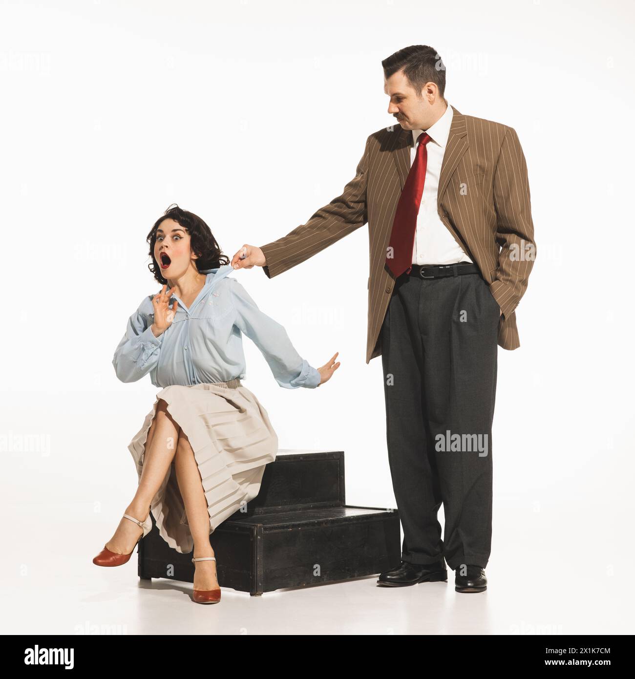 Man with displeased face pulling shocked elegant woman with her shirt ...