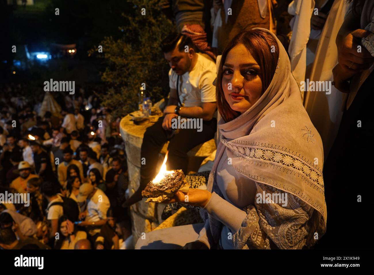Lalish, Iraq. 16th Apr, 2024. Iraqi Yazidi young woman lights candles ...
