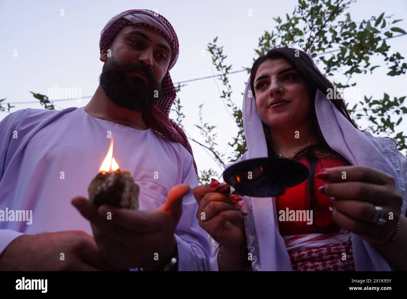 Lalish, Iraq. 16th Apr, 2024. An Iraqi Yazidis couple lights candles at ...