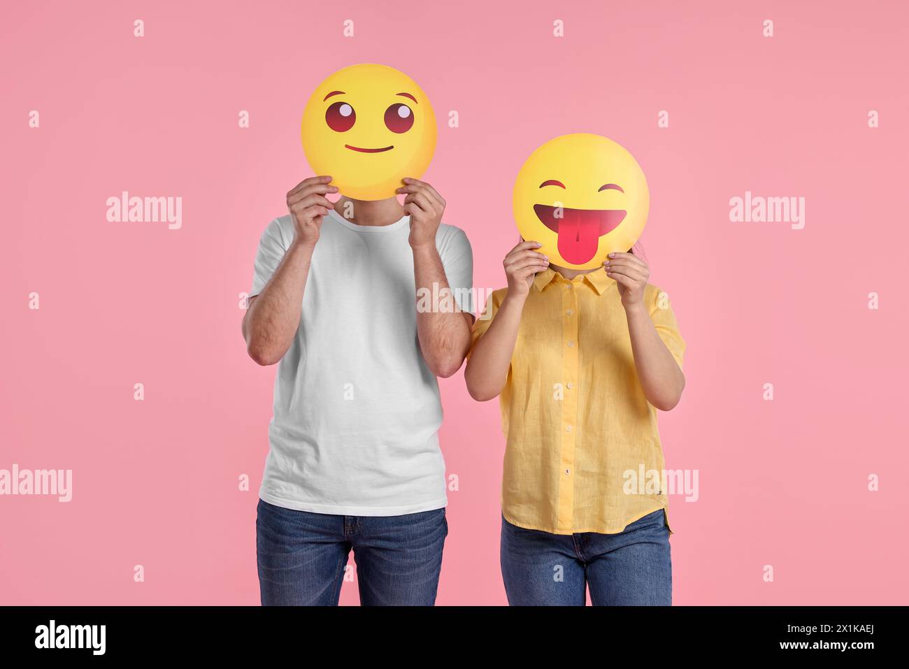 People covering faces with emoticons on pink background Stock Photo - Alamy