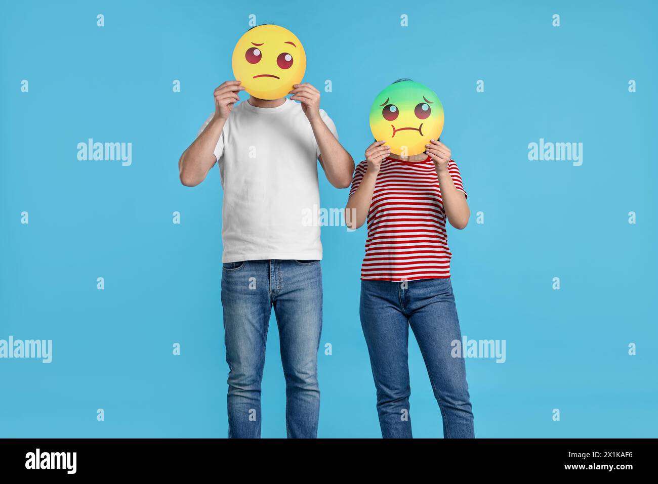 People covering faces with emoticons on light blue background Stock ...
