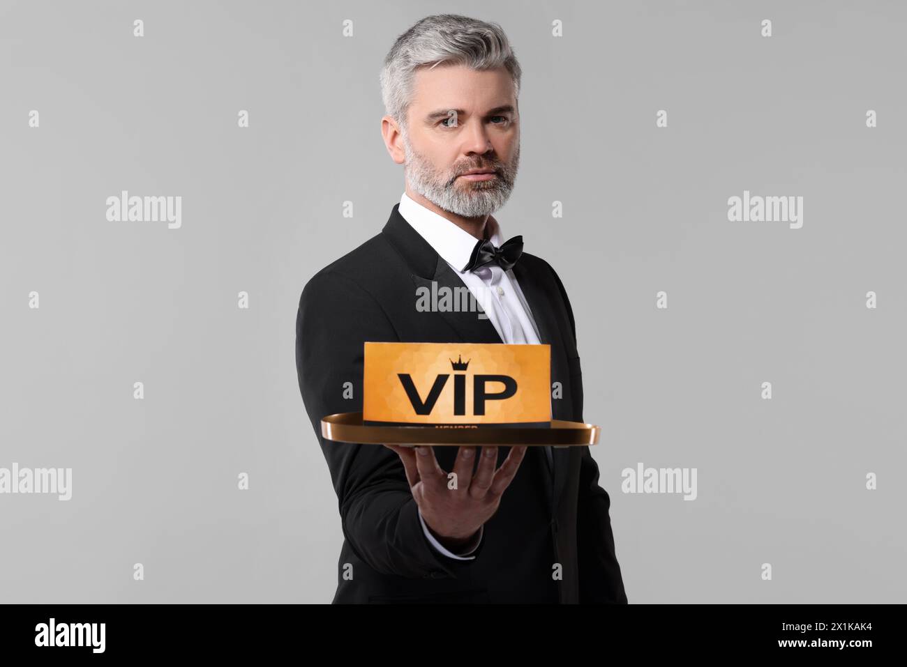 Handsome man holding tray with VIP sign on light grey background Stock ...