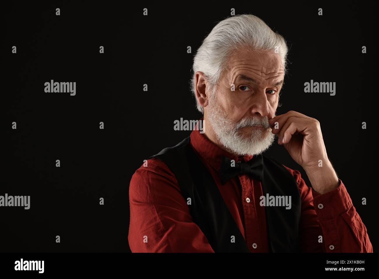 Senior man touching mustache on black background, space for text Stock ...